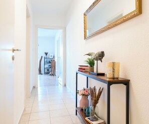 Um corredor com um aparador, um espelho e uma porta.