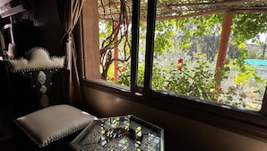 Quarto com vista para um jardim através de uma janela com treliça de madeira.