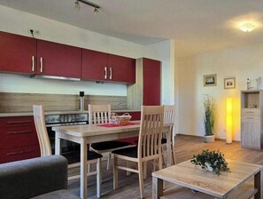 Cozinha compacta com armários vermelhos, mesa de madeira e cadeiras.