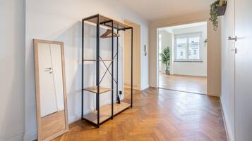 Um corredor com piso de madeira, um guarda-roupa de estrutura metálica e uma porta com uma toalha pendurada.