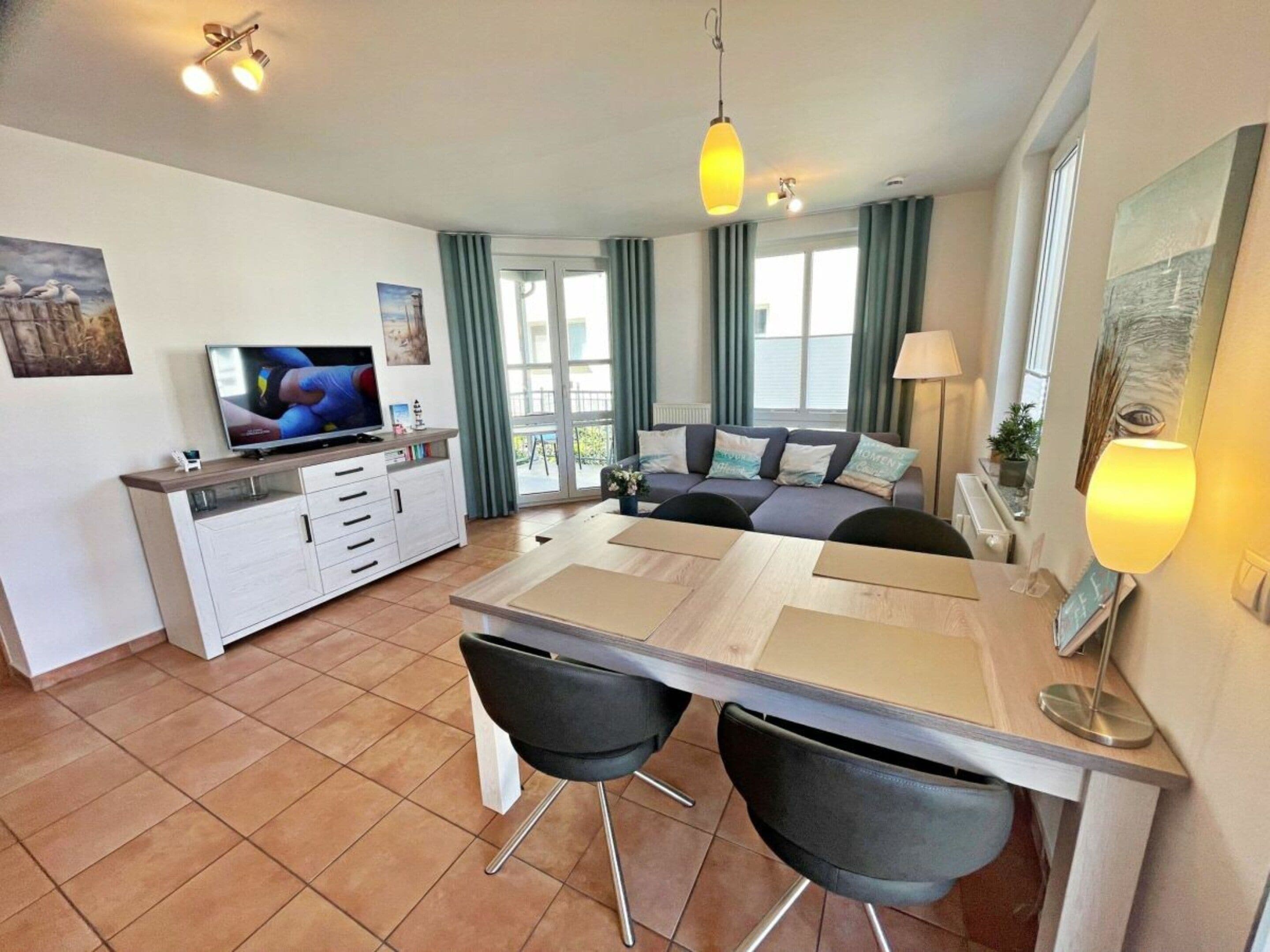 Uma sala de estar moderna com televisão, sofá, mesa de jantar e cadeiras.