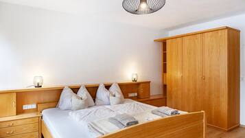 Quarto com cama de madeira, mesas de cabeceira, guarda-roupa e luminária pendente.
