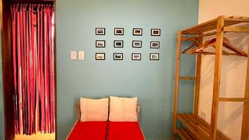 Quarto com cama, guarda-roupa de madeira e parede com quadros.