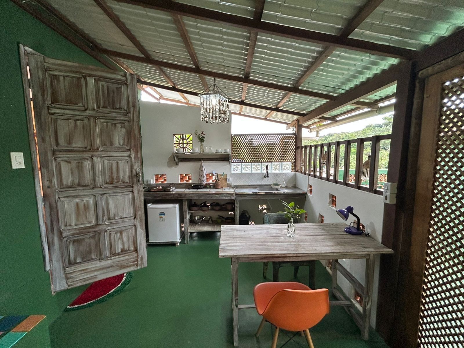 Cozinha compacta com geladeira, pia e mesa de madeira com cadeiras.
