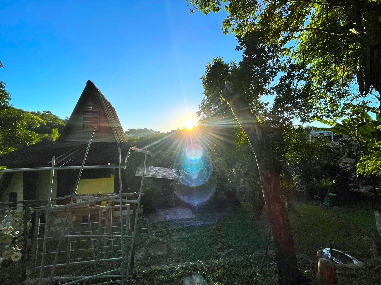 Uma casa de campo com telhado inclinado, rodeada por árvores e um céu limpo.