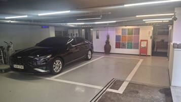 Garagem de estacionamento com um carro preto estacionado em uma vaga designada.