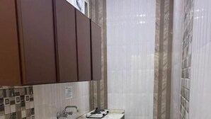 Uma cozinha com armários marrom escuro, bancada de mármore, pia e painel de azulejos.