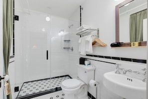 Uma casa de banho moderna com chuveiro, sanita e lavatório.