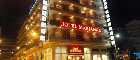 Um hotel com vários andares e uma placa chamativa com a inscrição 'HOTEL MARIANNA'.