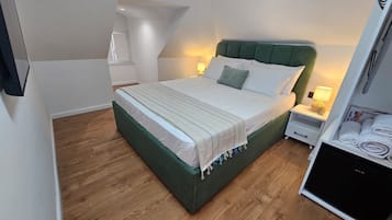 Quarto com cama, mesas de cabeceira e guarda-roupa.