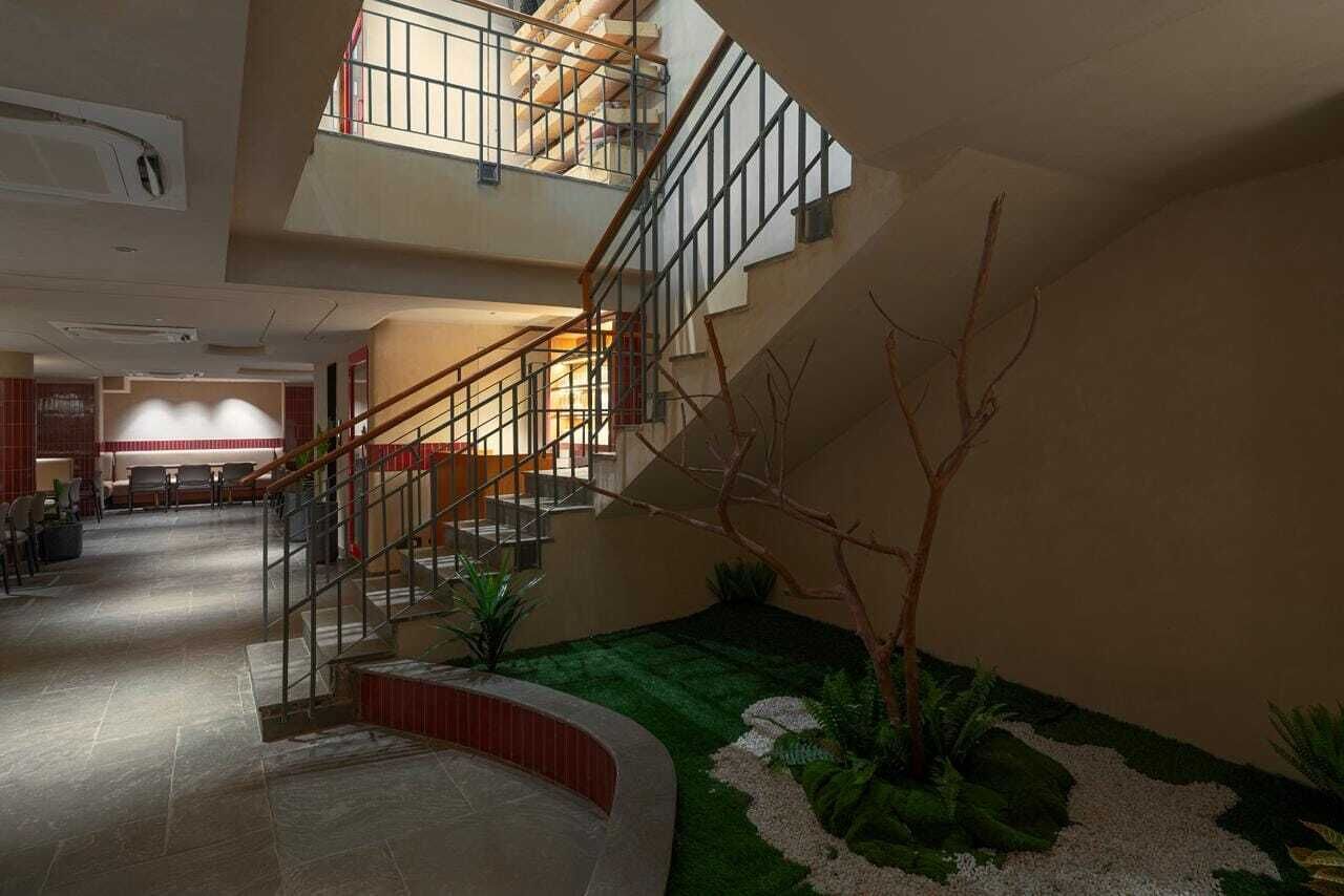 Um interior com vários níveis, com escada, plantas em vasos e um espaço de estar.