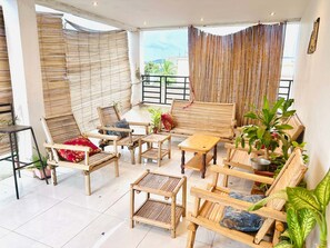 Varanda espaçosa com mobiliário de bambu, incluindo cadeiras e uma mesa, e vista para a região ao redor.