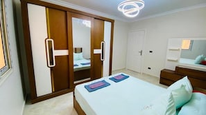 Quarto com cama, guarda-roupa, espelho e luminária no teto.