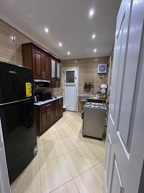 Cozinha equipada com frigorífico, fogão, micro-ondas e armários.