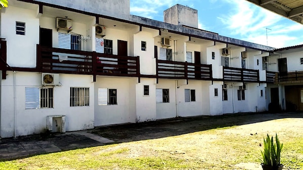 Um edifício com várias janelas, algumas com grades, e telhado plano.