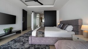 Quarto moderno com cama, mesas de cabeceira, televisão e ventoinha de teto.