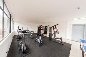 Uma academia com diversos equipamentos de ginástica, uma porta e uma janela.