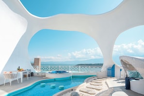 Área da piscina com hidromassagem, assentos e vista para o mar.