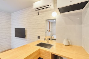 Uma casa de banho moderna com uma toucador de madeira, uma pia, um espelho, um ar condicionado fixado na parede e uma chaleira branca.