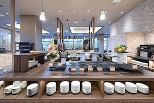 Interior moderno de restaurante com balcão central, diversas áreas de estar e parede de tijolos.