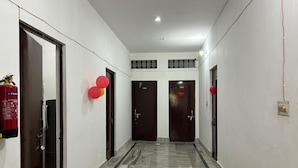 Um corredor com piso de mármore, portas e balões vermelhos.