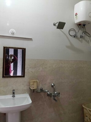 Casa de banho com lavatório branco, espelho, porta-toalhas e chuveiro.