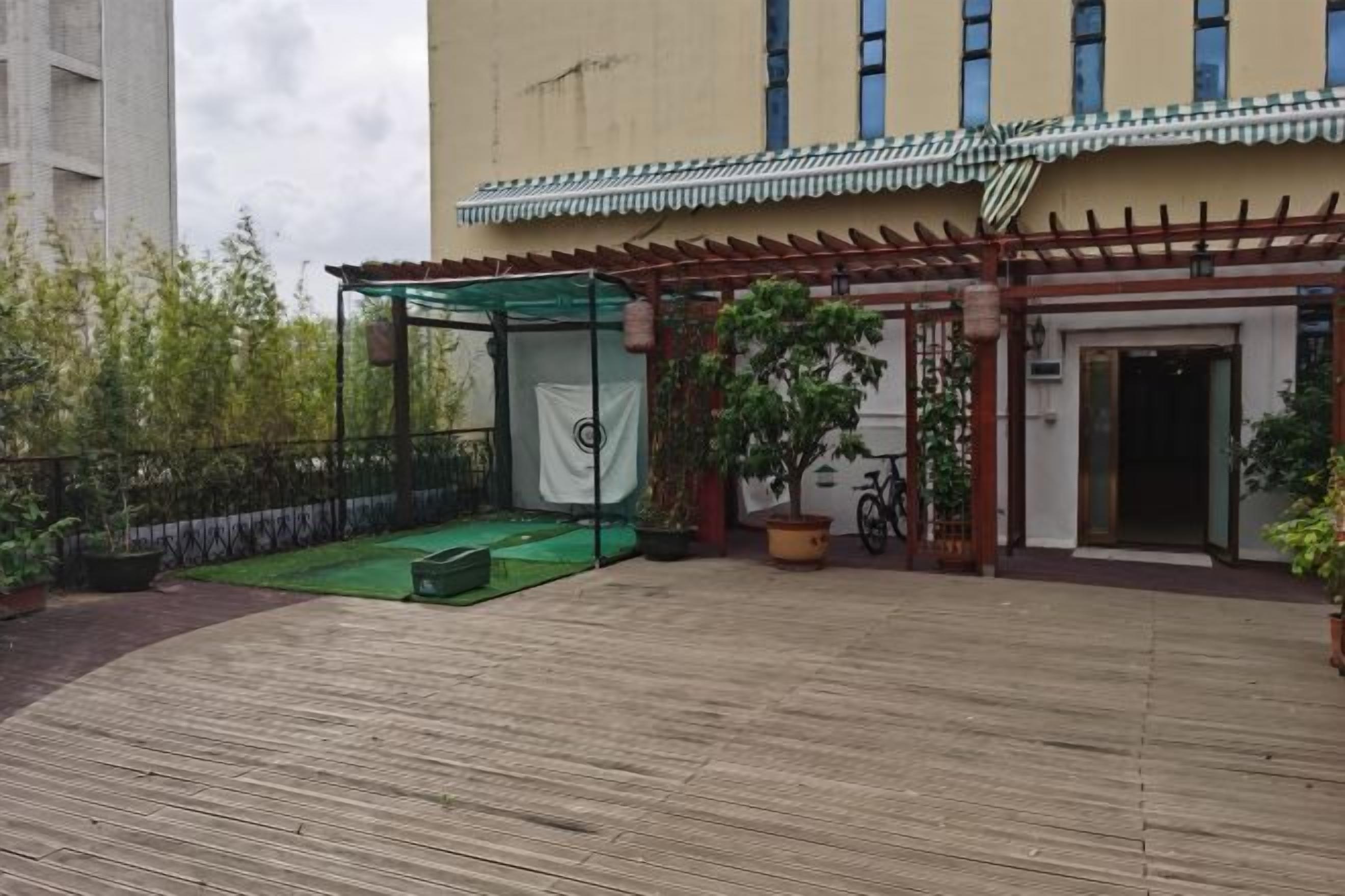 Um pátio com deck de madeira, área de estar coberta e entrada de um edifício.