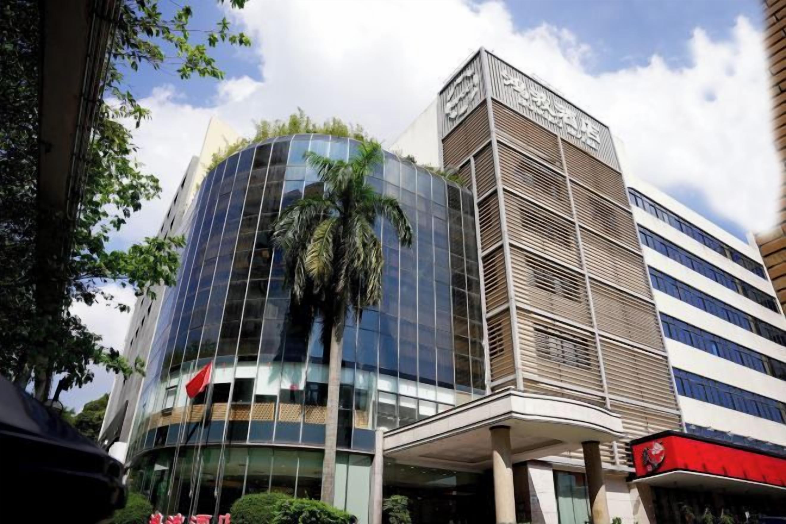 Um edifício moderno com fachada de vidro curva e estrutura de telhado plano com linhas horizontais.