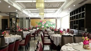 Uma sala de jantar com mesas redondas, cadeiras e centros de mesa florais.
