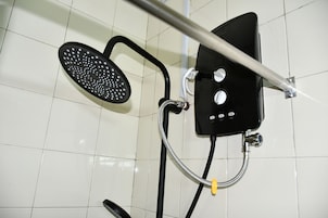 Chuveiro com chuveiro manual, painel de controle fixado na parede e escova manual.
