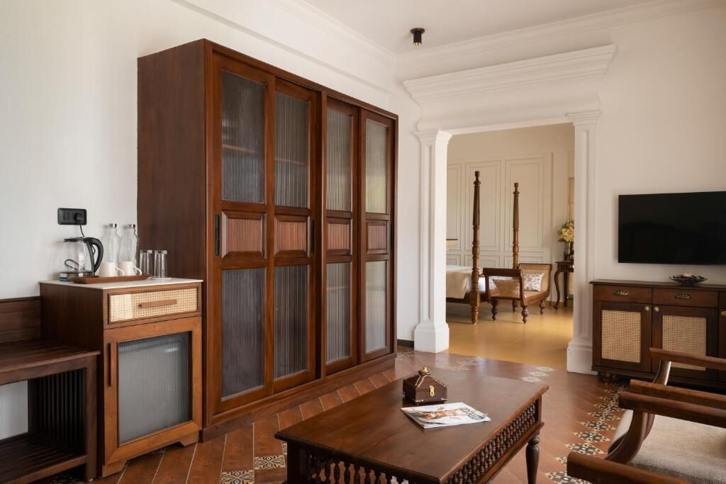 Quarto com armário de madeira, televisão, mesa de jantar e uma cadeira.