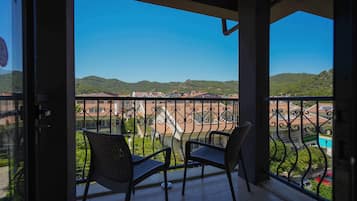 Uma varanda com duas cadeiras e vista para uma área residencial, com casas e colinas.