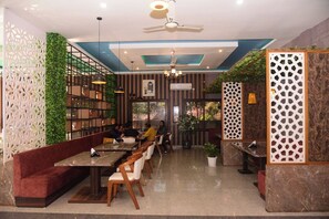 Restaurante com mesas internas, ventilador no teto e vista pela janela.