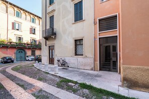 Rua estreita com edifícios, uma bicicleta e carros estacionados.