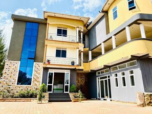 Edifício residencial com vários andares, entrada central, varandas e garagem.