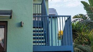 Um edifício com fachada verde clara, escadaria azul e guarda-corpo de metal na varanda.