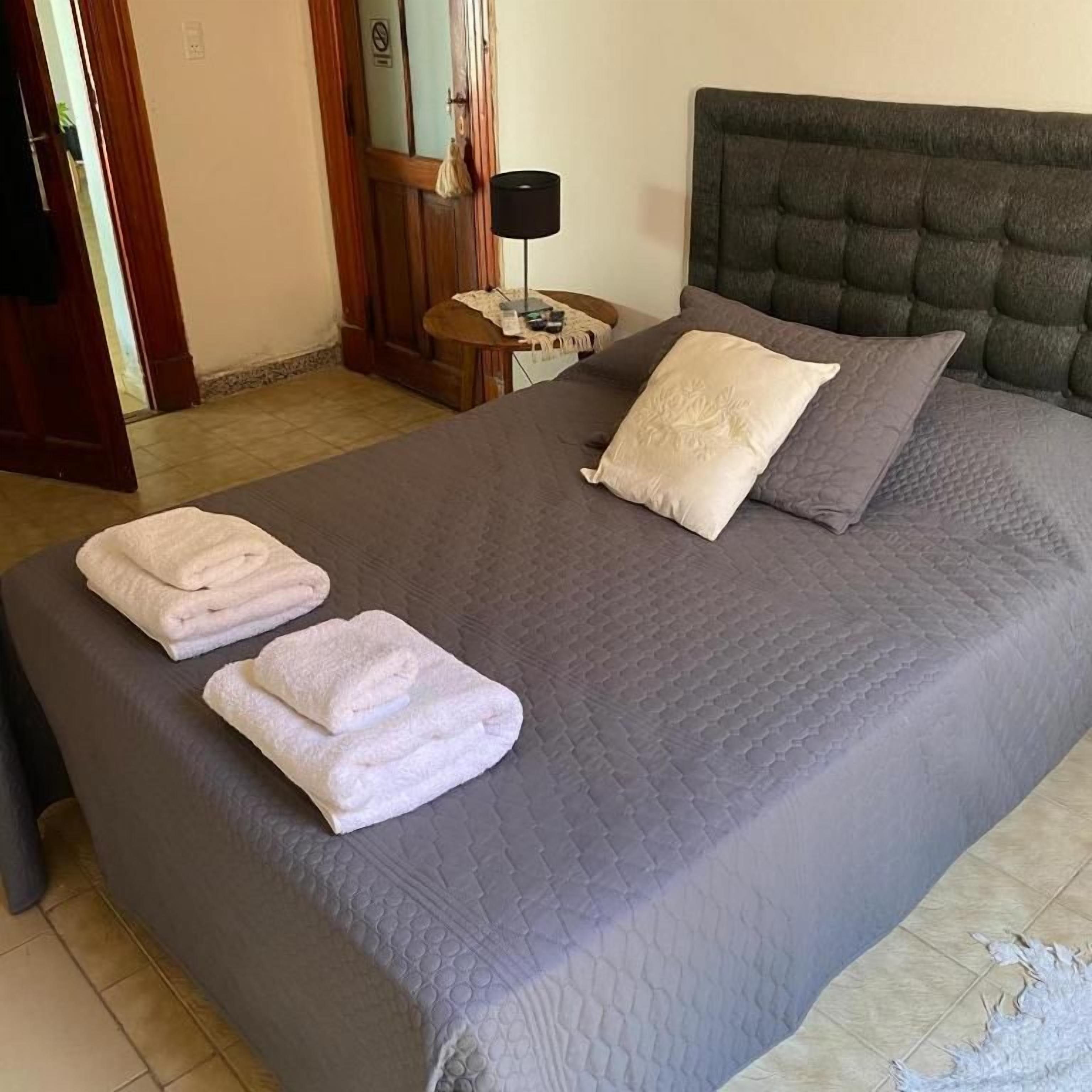 Cama arrumada com travesseiros e toalhas dobradas.