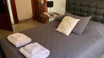 Cama arrumada com travesseiros e toalhas dobradas.