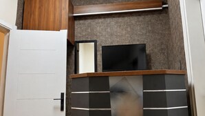 Quarto com cama embutida, televisão e porta.