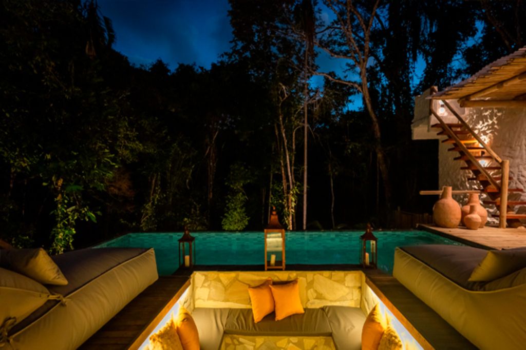 Uma área de estar ao ar livre com piscina, rodeada por árvores.