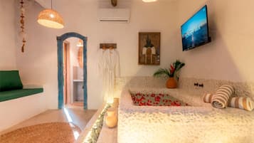 Um quarto de spa com banheira de pedra, televisão e um quadro na parede.