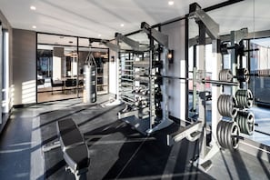 Academia moderna com diversos equipamentos de musculação, incluindo suporte para agachamento e kettlebells.