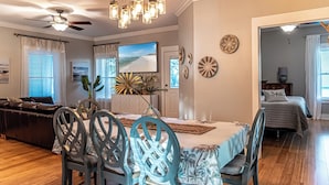 Uma área de refeições com uma mesa posta para quatro pessoas, cercada por cadeiras com design tropical.