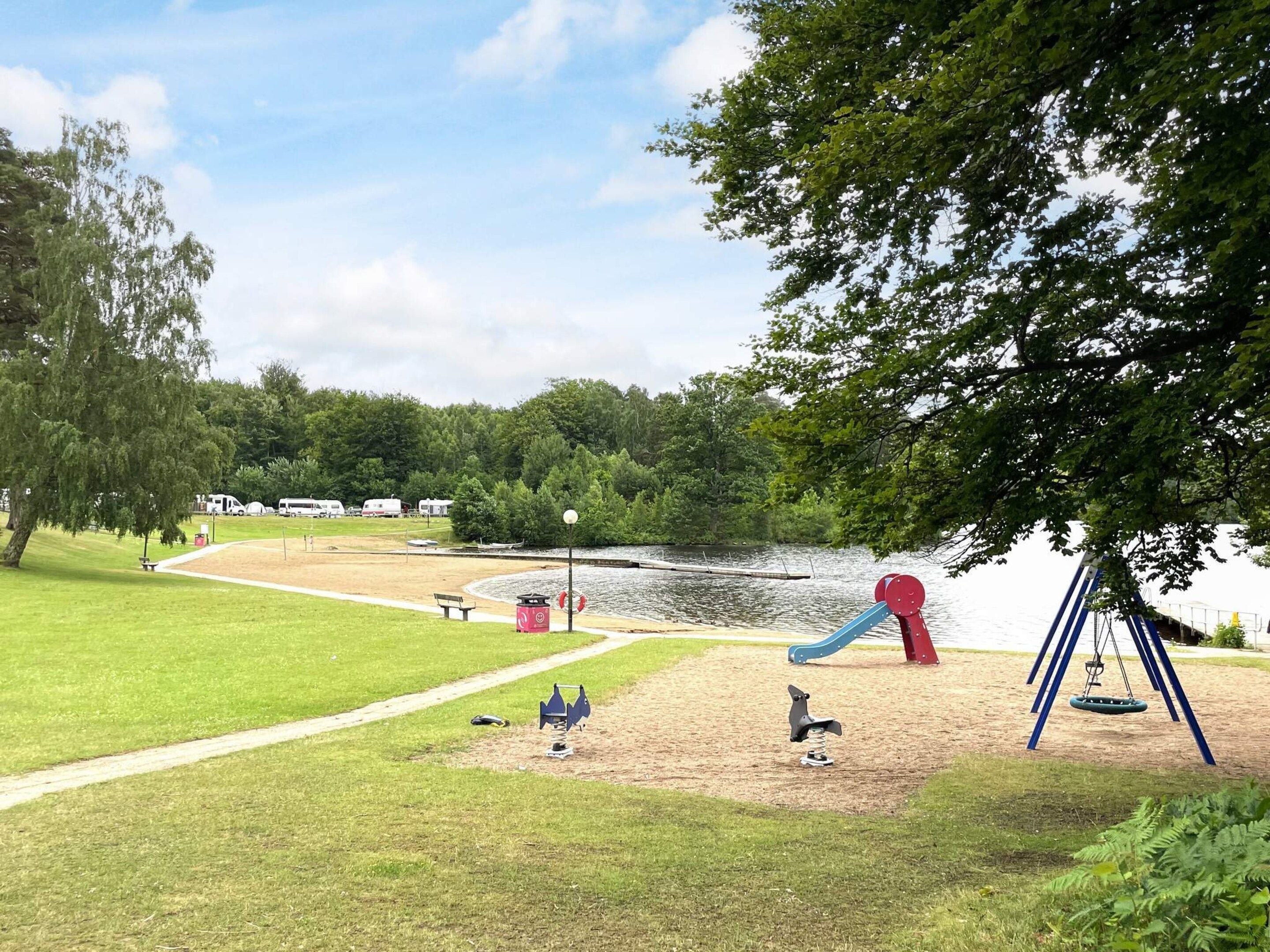 Um parque com parquinho, lago e áreas para piquenique.
