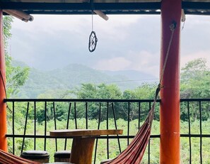 Uma rede, uma mesa e vista para uma paisagem montanhosa.