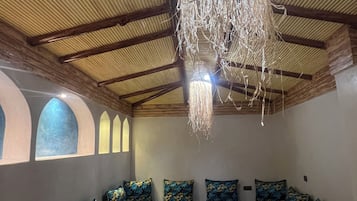 Um quarto com uma mesa comprida e bancos, um lustre pendurado e janelas em arco.