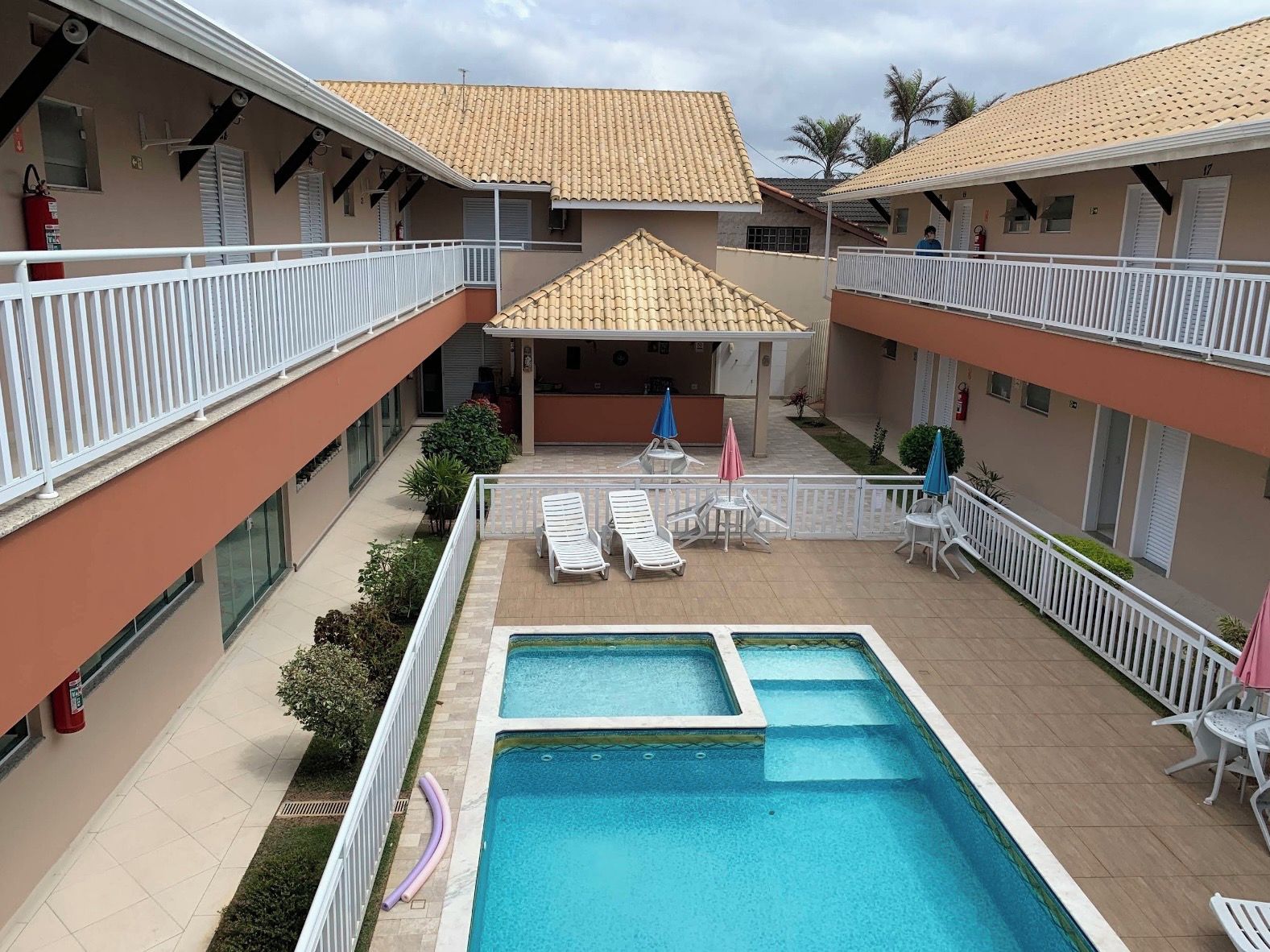 Hotel com piscina, área de estar externa e um pátio coberto.