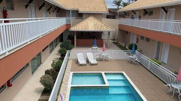 Hotel com piscina, área de estar externa e um pátio coberto.