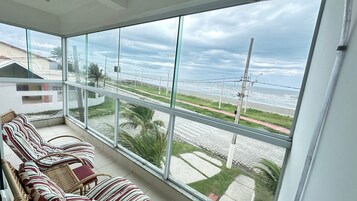 Varanda com móveis de vime e vista para a praia e oceano.