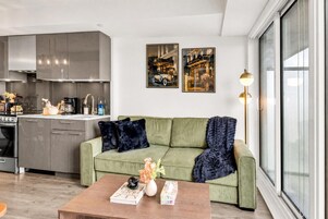 Uma sala de estar moderna com um sofá verde, uma mesa de centro e uma estante de livros.
